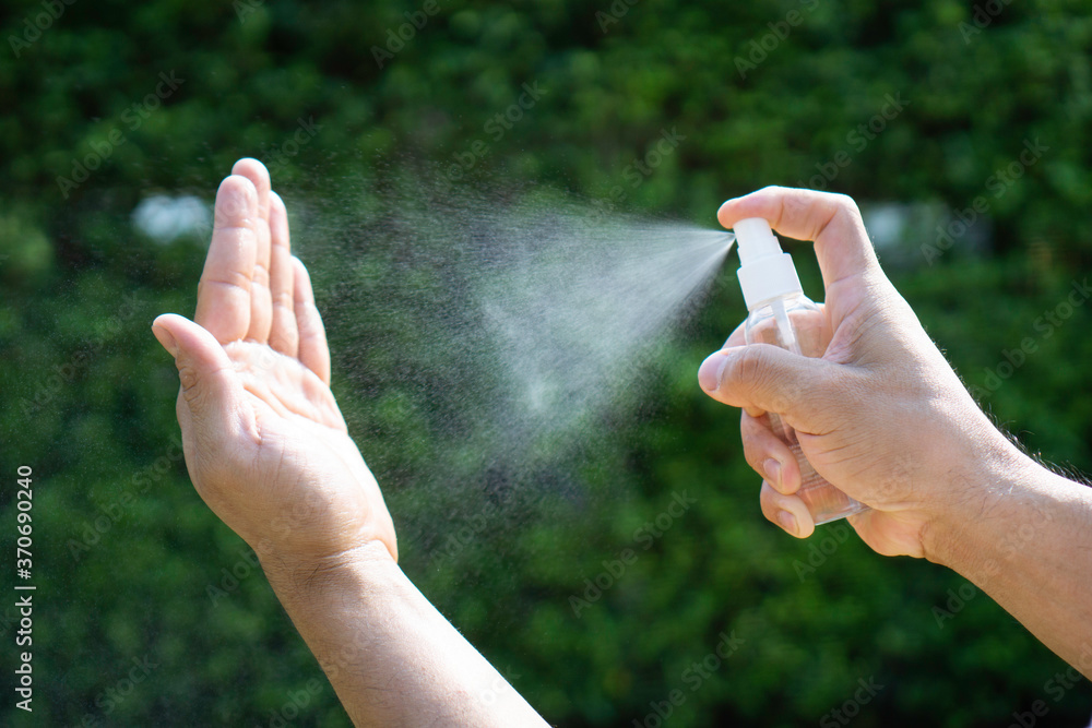An Asian man is spraying 70 percent alcohol-based sprays on his hands ...