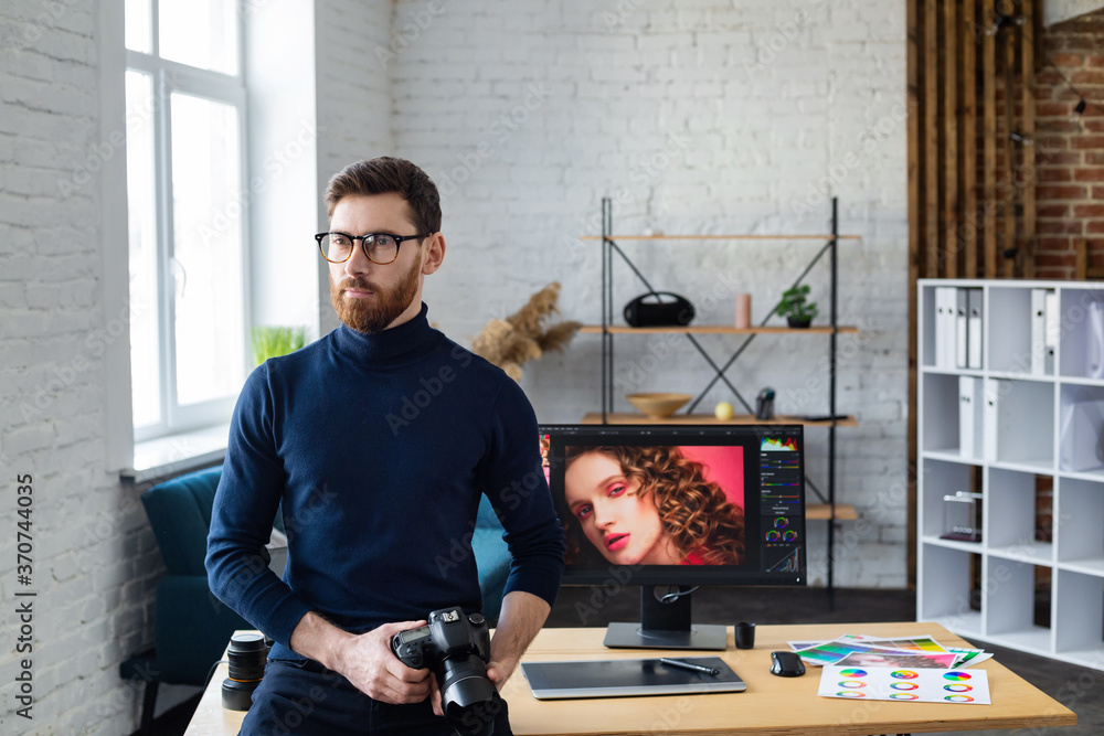 Portrait of professional photographer holding camera in photo studio ...