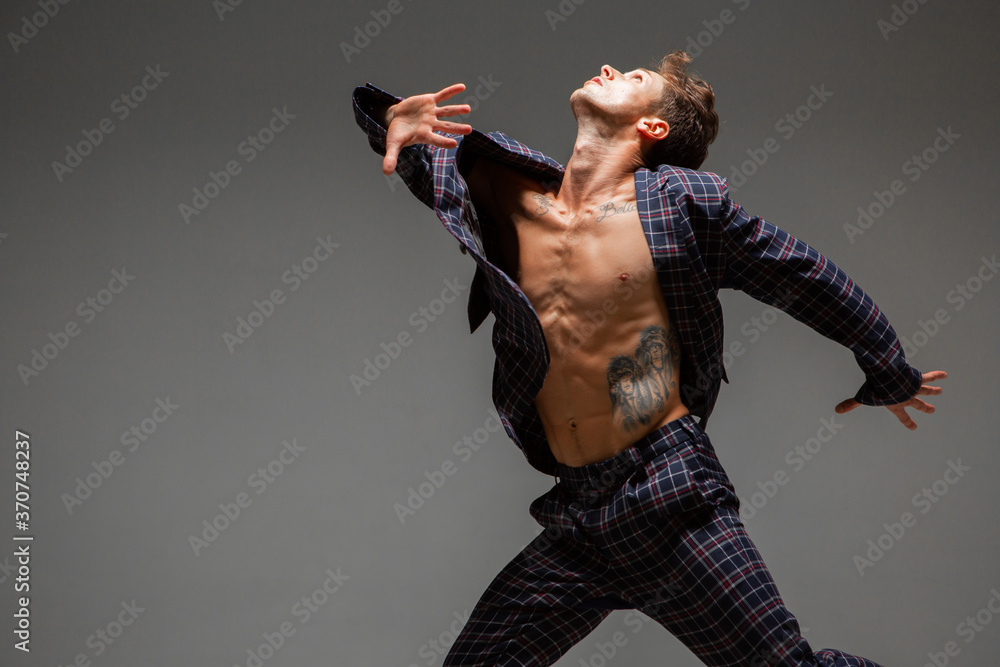Cool young guy dancer in suit dancing modern expressive dance in studio ...