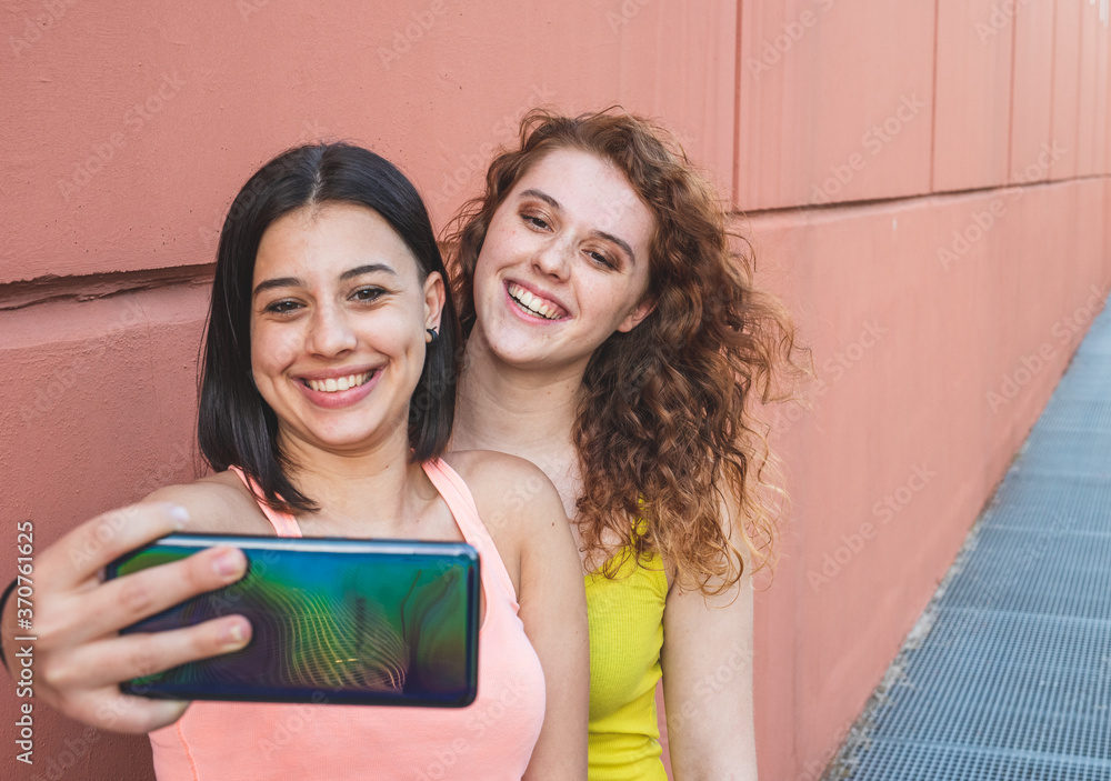 two girls of generation z take pictures with their mobile phones around ...