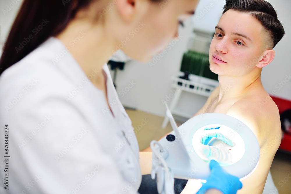 doctor dermatologist-a young woman examines the skin condition of a ...