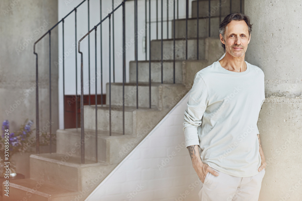Portrait of a senior man leaning against a column in a loft flat Stock ...