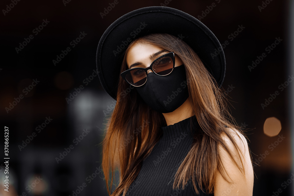 beautiful woman in a black medical protective mask on her face, dressed ...