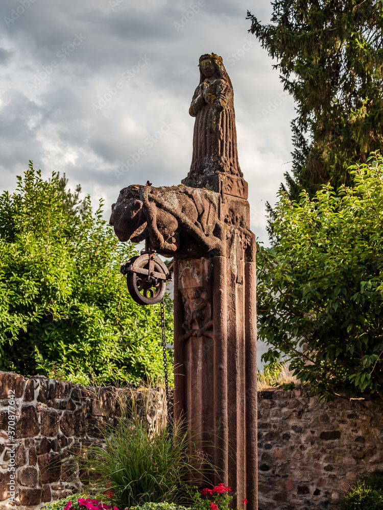 Medieval stone statue over an old well, Alsace, territory of Andlau ...
