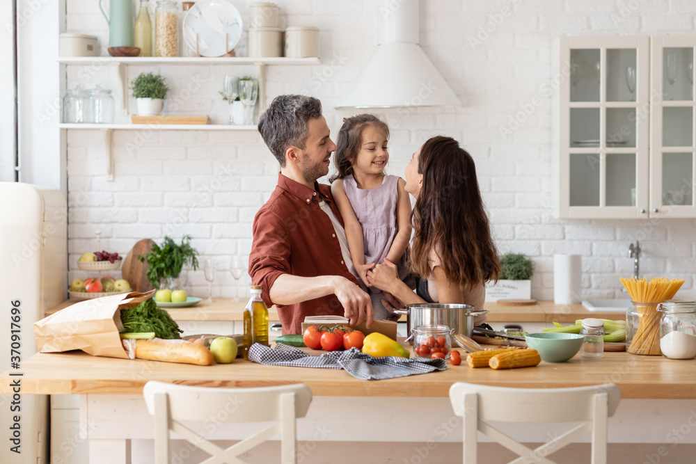 Happy parents with daughter cooking on kitchen Stock Photo | Adobe Stock