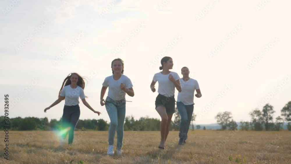 A happy family runs in the park at sunset. A team of people running ...