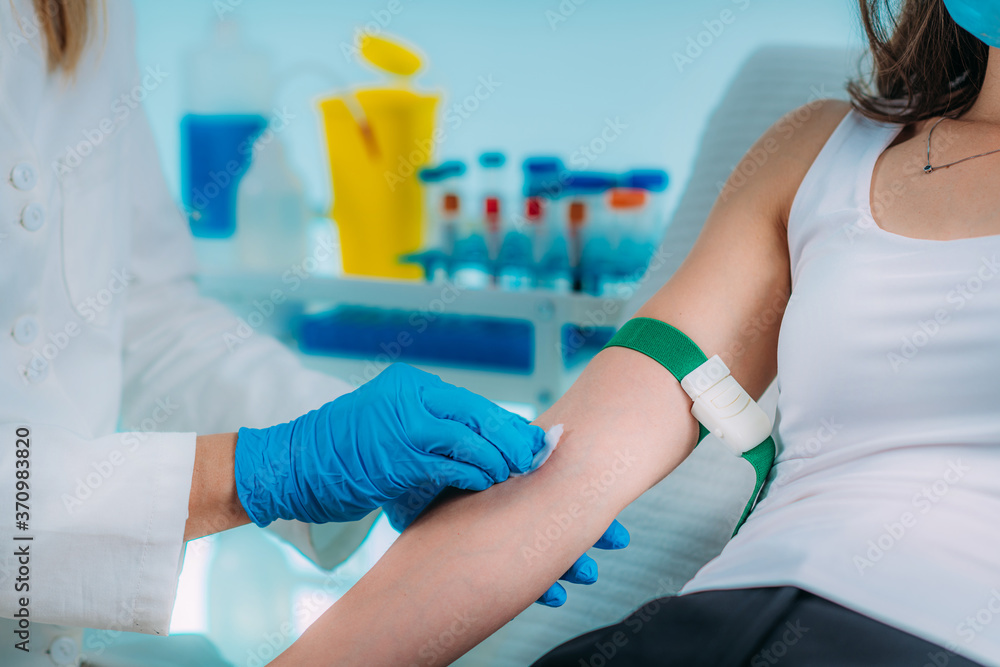 Medical worker with PPE taking blood sample from patient in a hospital ...