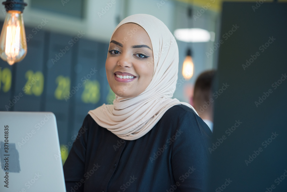 Muslim business lady wearing hijab and working at computer in office ...