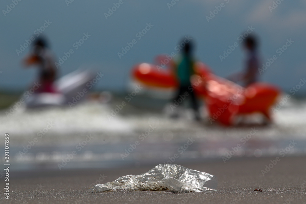 Single use plastic bag washed up on the beach as beach goers enter the ...