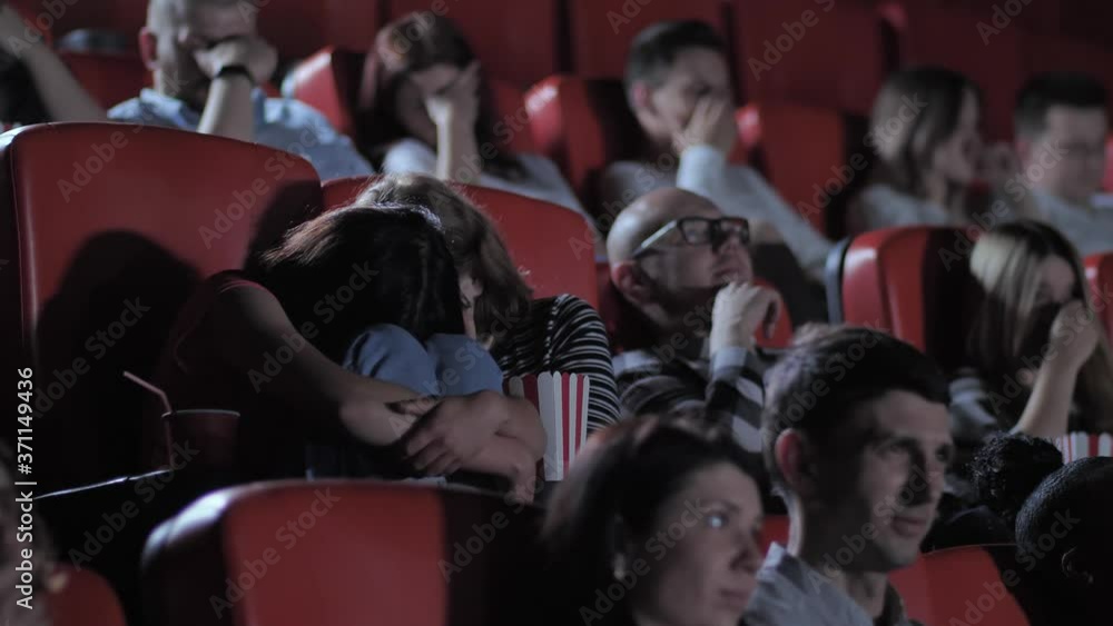 Scared audience watching thriller and covering their eyes with hands ...