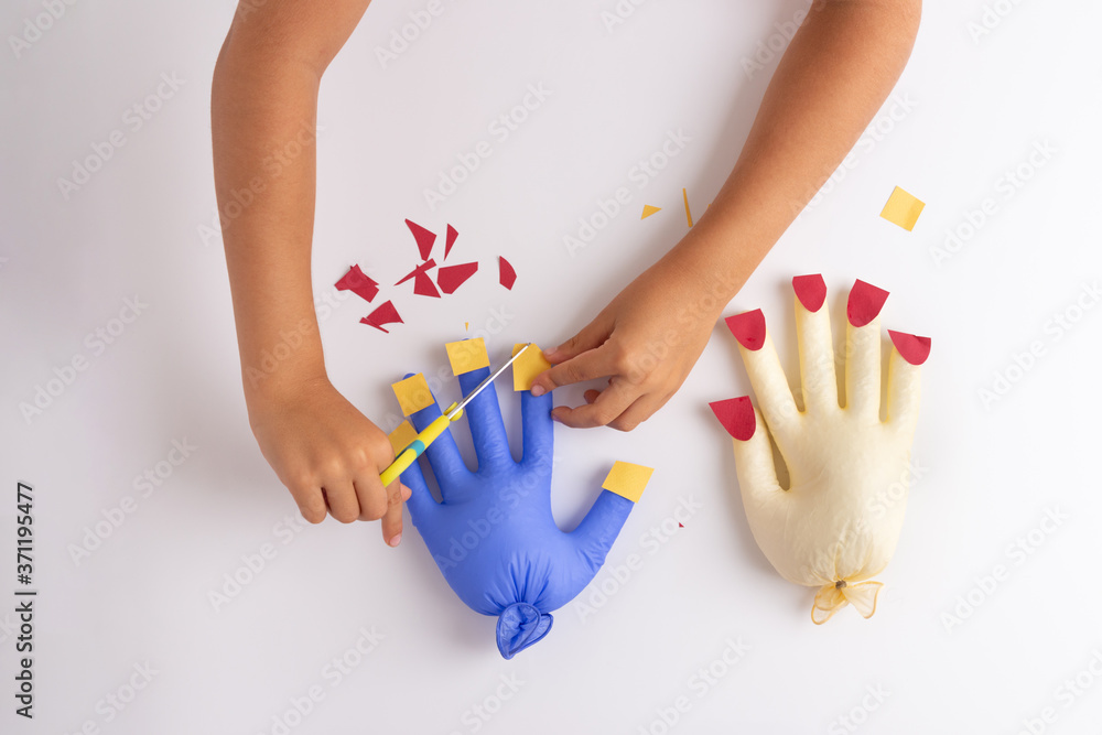 kids hand cutting paper artificial nails on a toy, practicing scissors ...