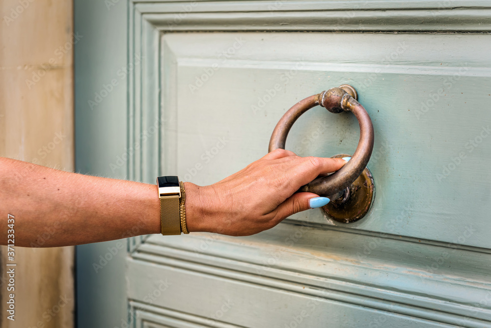 Close-up woman hand knocking wooden olive colour wooden door, in front ...