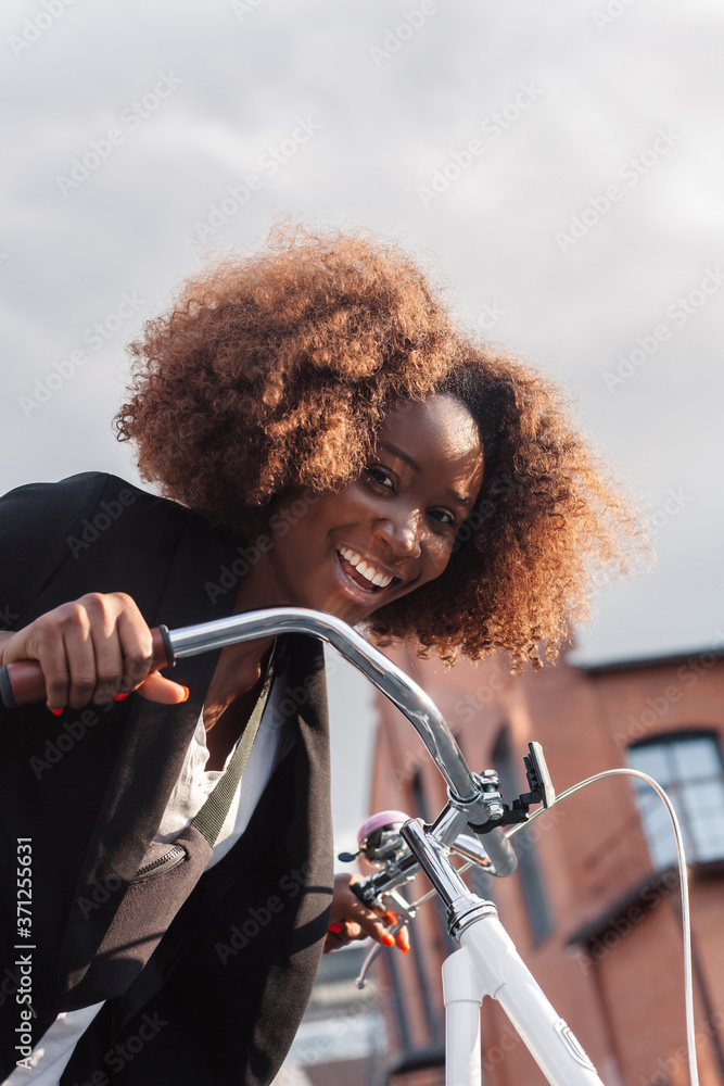 Pretty young black african american woman riding bicycle on the street ...