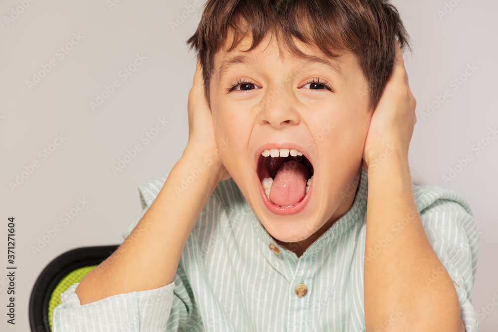 Sad screaming autistic boy portrait close ears with hands, sensory ...