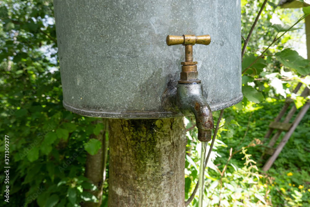 Antique metal washbasin with a tap. Water tank with a faucet for ...