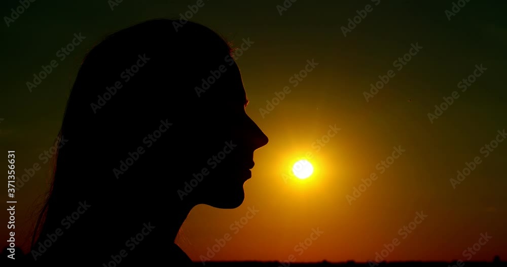 Macro contrast profile of female face kissing sun on saturated sunset ...