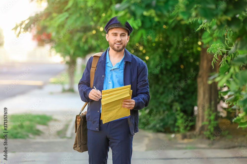 Handsome young postman with letters outdoors Stock Photo | Adobe Stock