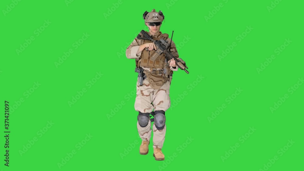 Soldier of special force walking and shooting with a rifle on a Green ...