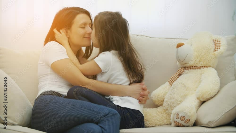 Cute little kid girl and mother embracing each other, smiling, touching ...