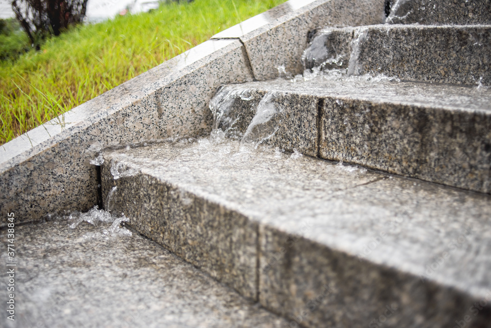 The stream of water flows down from the steps of the stairs. Heavy rain ...