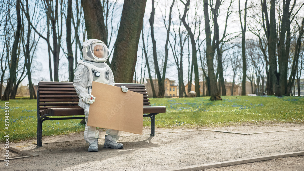 Sad Man in Spacesuit is Sitting on a Bench in a Park and Holding a ...