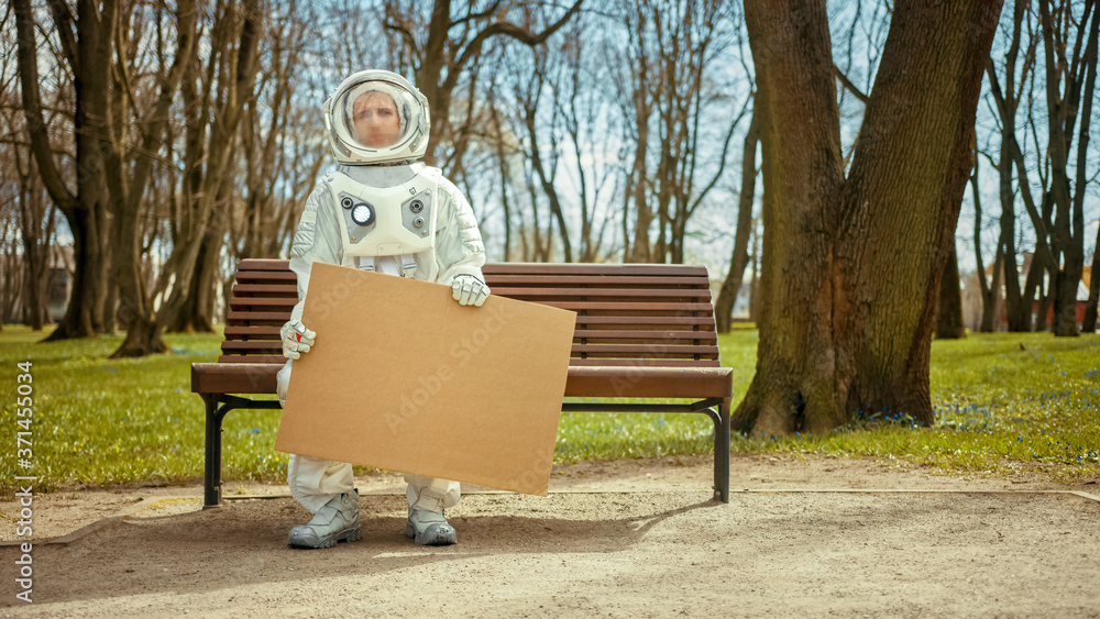 Sad Man in Spacesuit is Sitting on a Bench in a Park and Holding a ...
