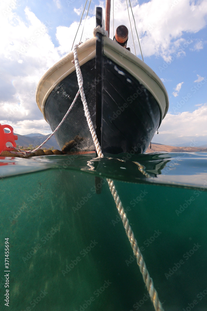 Underwater split photo of traditional classic wooden fishing boat ...