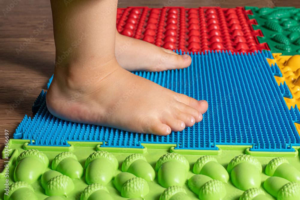 The legs of a small child on orthopedic mats. Bright surfaces for ...
