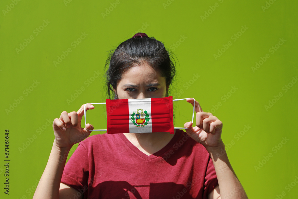 A woman and hygienic mask with Peru flag pattern in her hand and raises ...