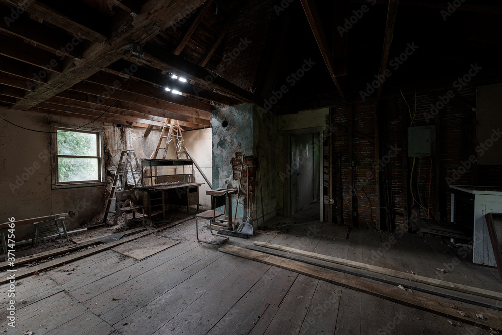 Inside a derelict attic with sketchy stacked furniture below a hole in ...