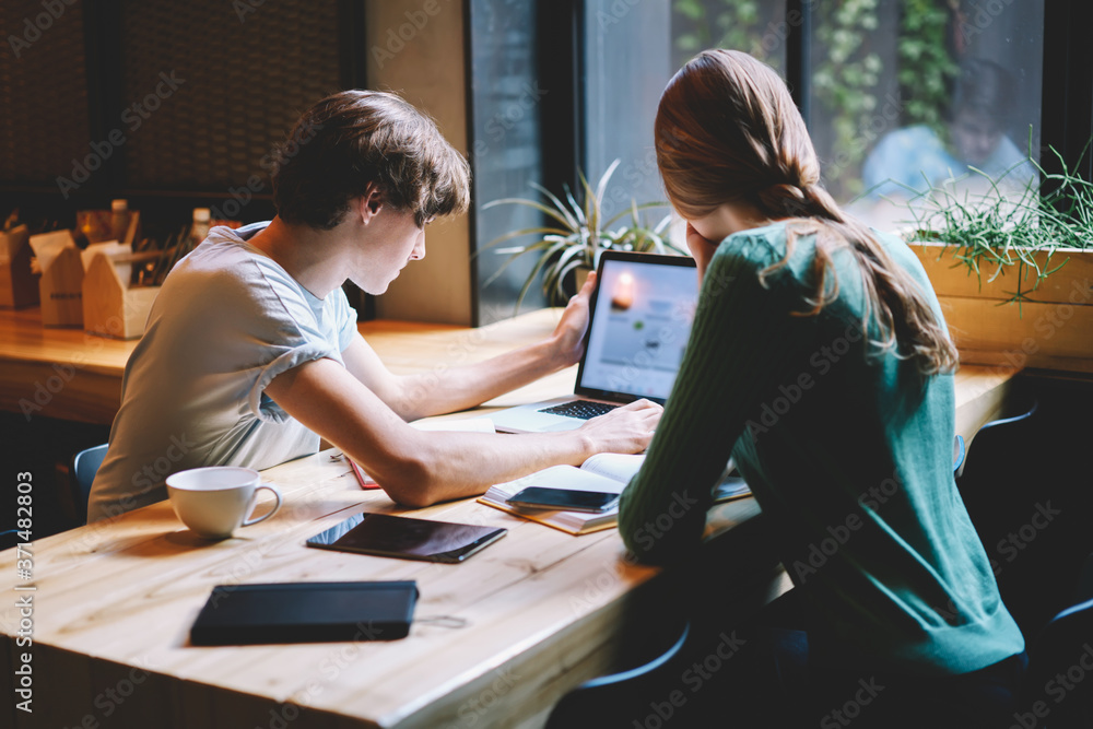 Back view of talented students browsing useful information for ...