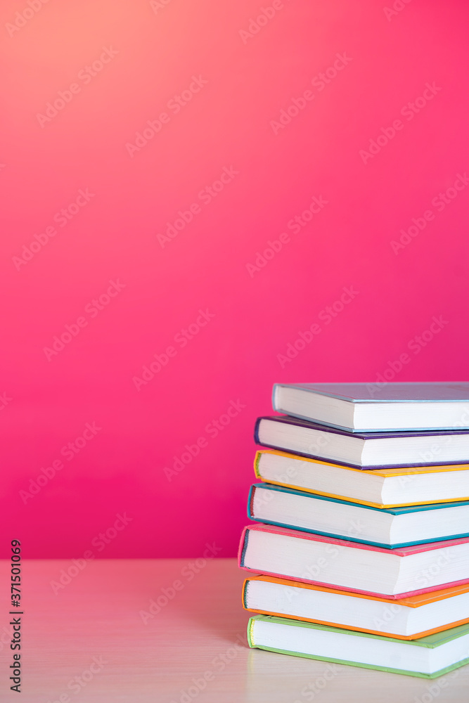 Stack of colorful books, bright colorful pink background, free copy ...