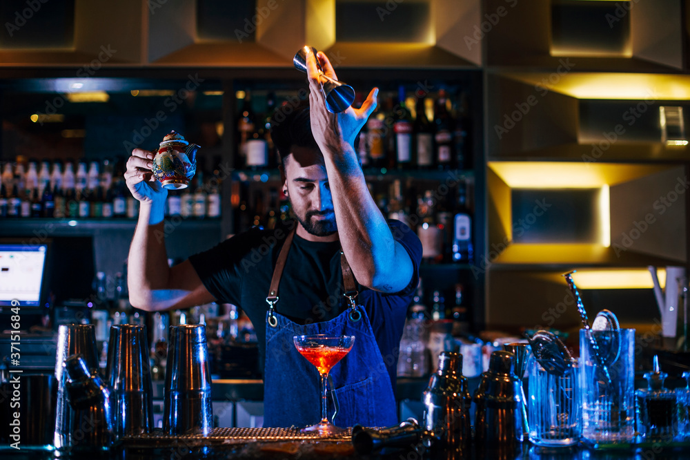 Foto de Male bartender making cocktails on bar counter in pub at night do Stock | Adobe Stock