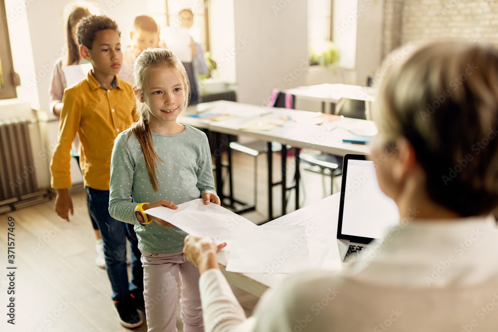 Elementary students taking their test results from a teacher in the ...