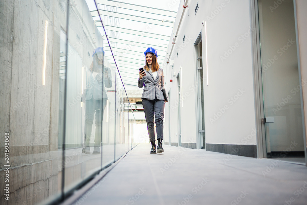 Young attractive female architect walking around building in ...