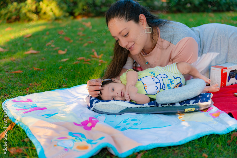 Madre cuidando a su hijo bebé con amor sobre el césped acostado recién ...