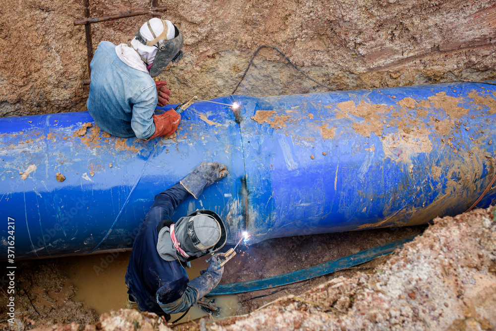 Two workers are connecting underground sewers at a construction site to ...