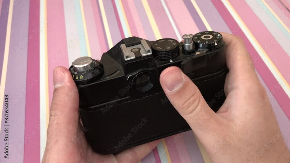 Close-up of male hands. Man is changing the shutter speed setting and ...