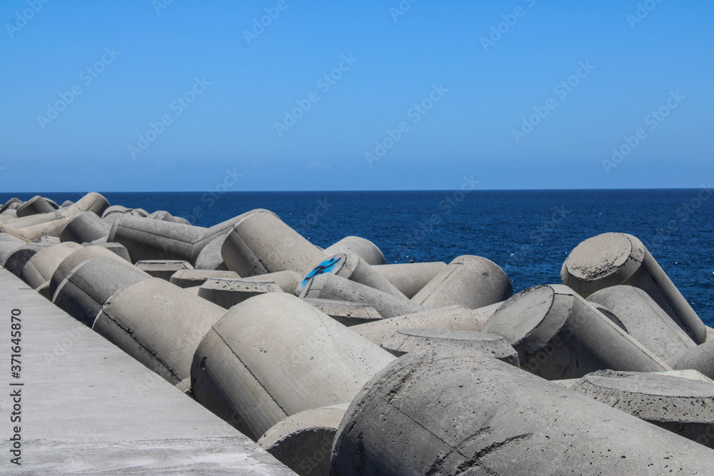 Grandes rocas rompeolas en las costas del mar con un cielo azul Stock ...