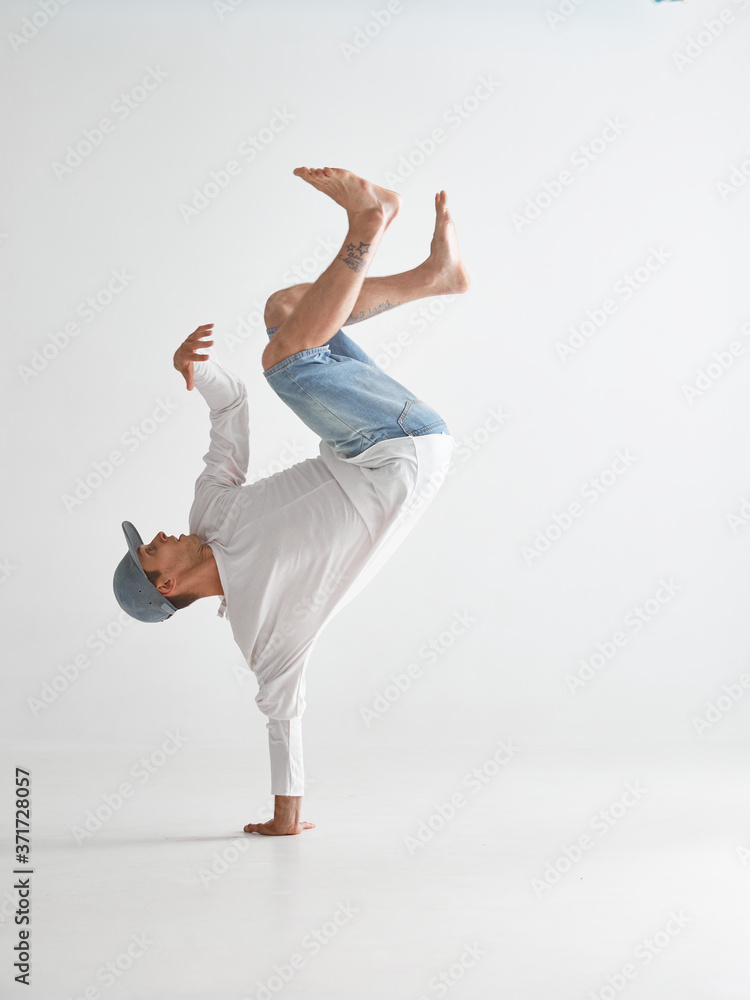 Young breakdancer stands on one arm dancing hip-hop isolated on white ...