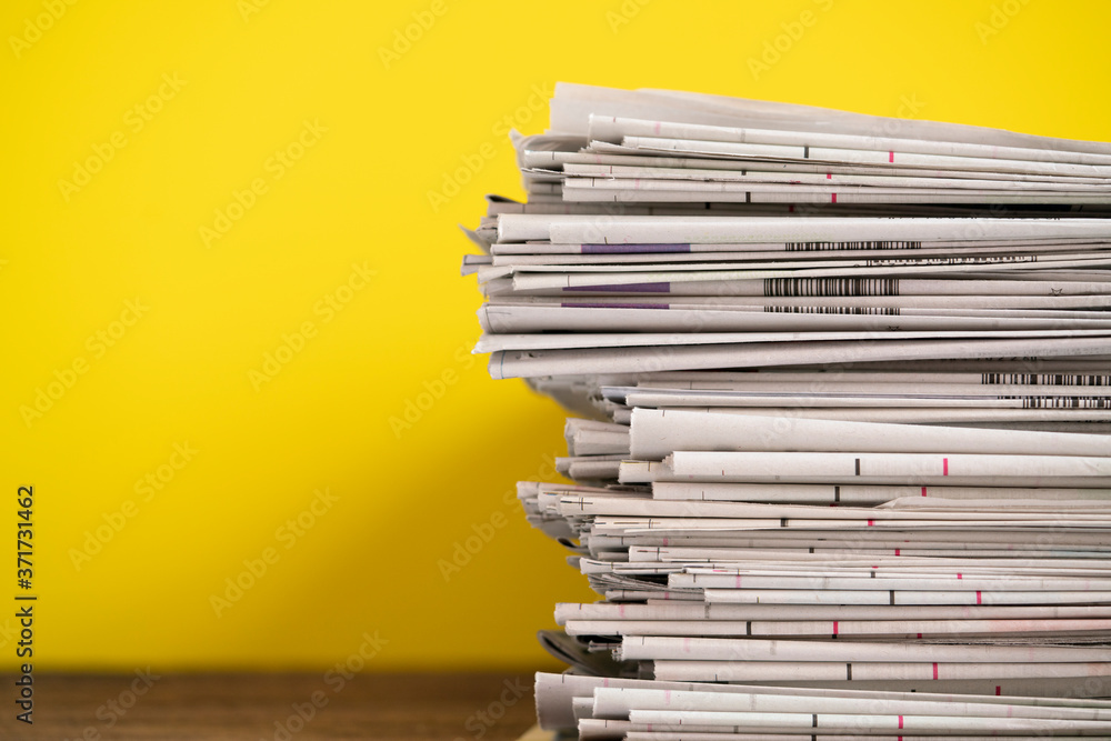 close up newspapers folded and stacked on yellow background on the ...