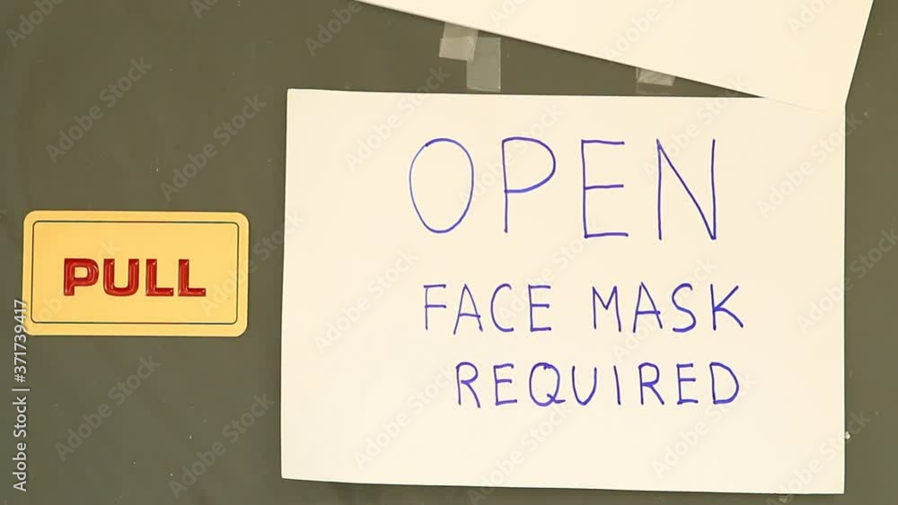 Man pull out Close covid-19 board to reveal Open face mask required ...