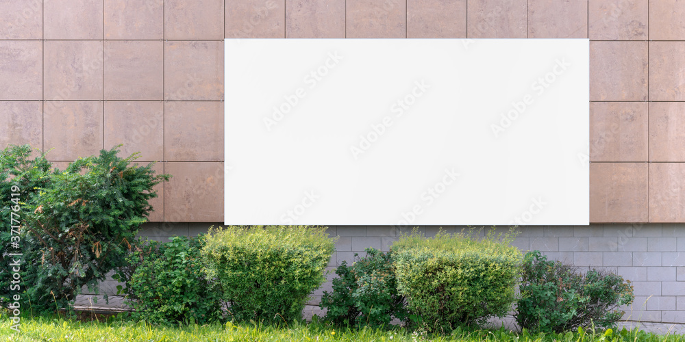 large white banner with mock up on empty building wall with green bush ...