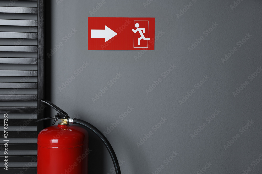Fire extinguisher and emergency exit sign indoors. Space for text Stock ...