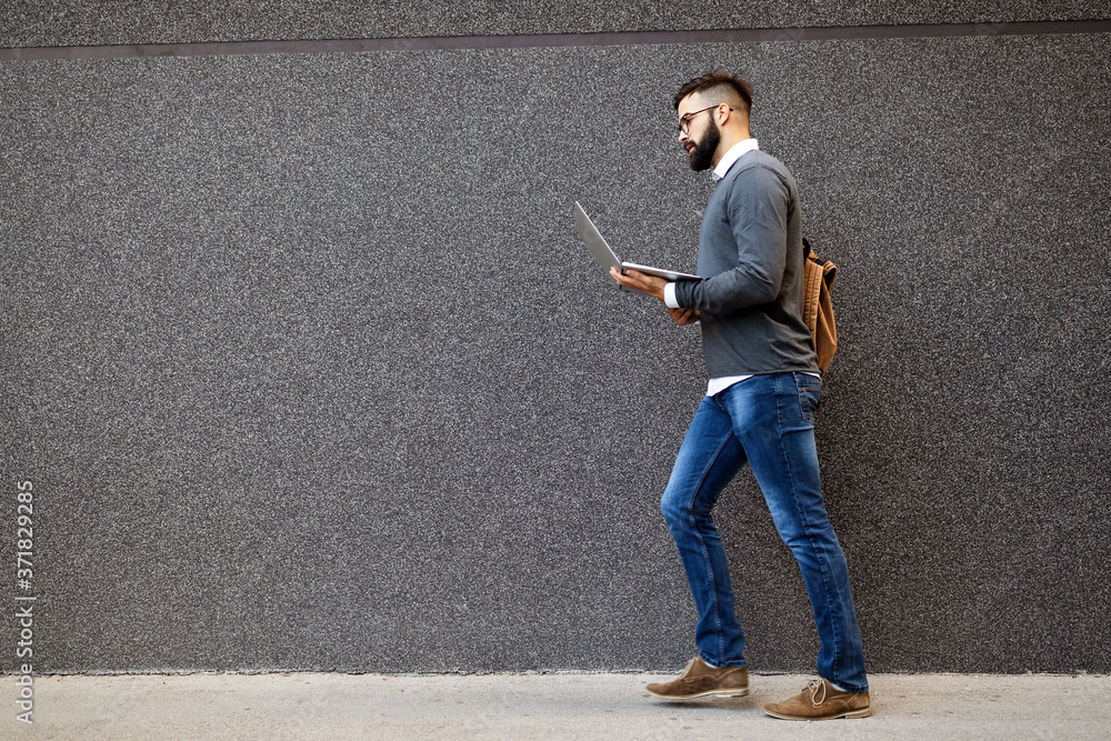 Businessman walking in street holding his laptop, working outdoor Stock ...