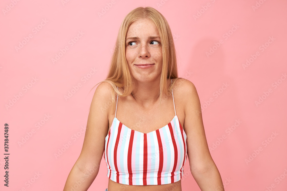 Studio shot of emotional timid European teenage girl in stylish striped ...