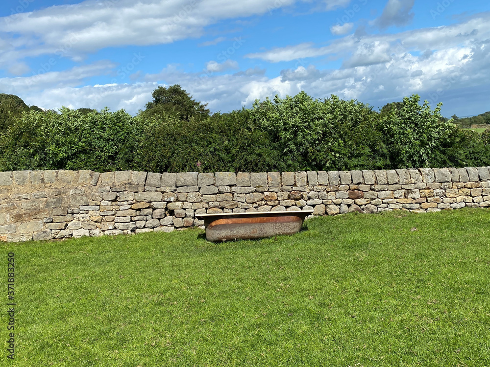 Old bath, in a field, used as a water trough, next to a dry stone wall ...