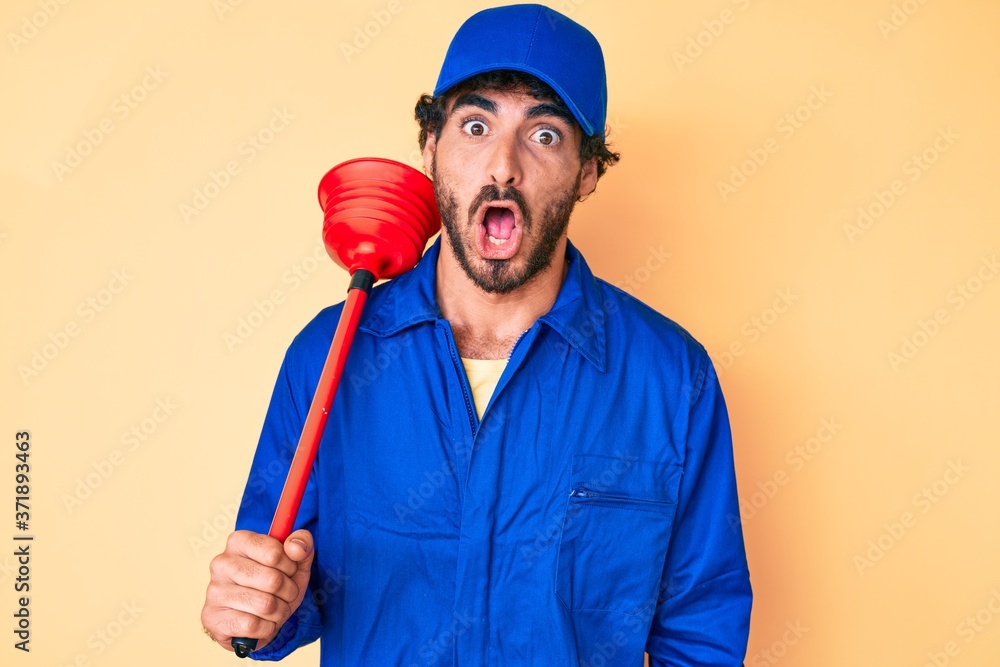 Handsome young man with curly hair and bear wearing plumber uniform ...
