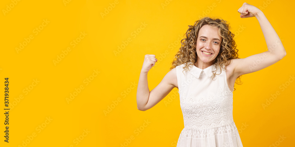 A strong woman with curly hair, a toothy smile, raises her arms and ...