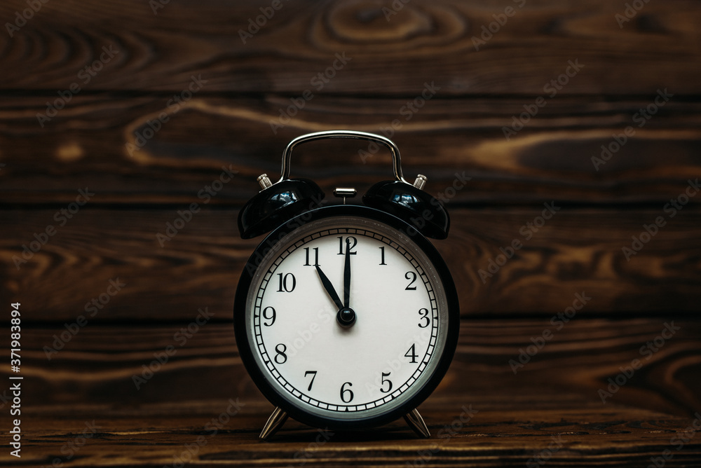 Clock on a wooden background. The clock shows the time of eleven o ...